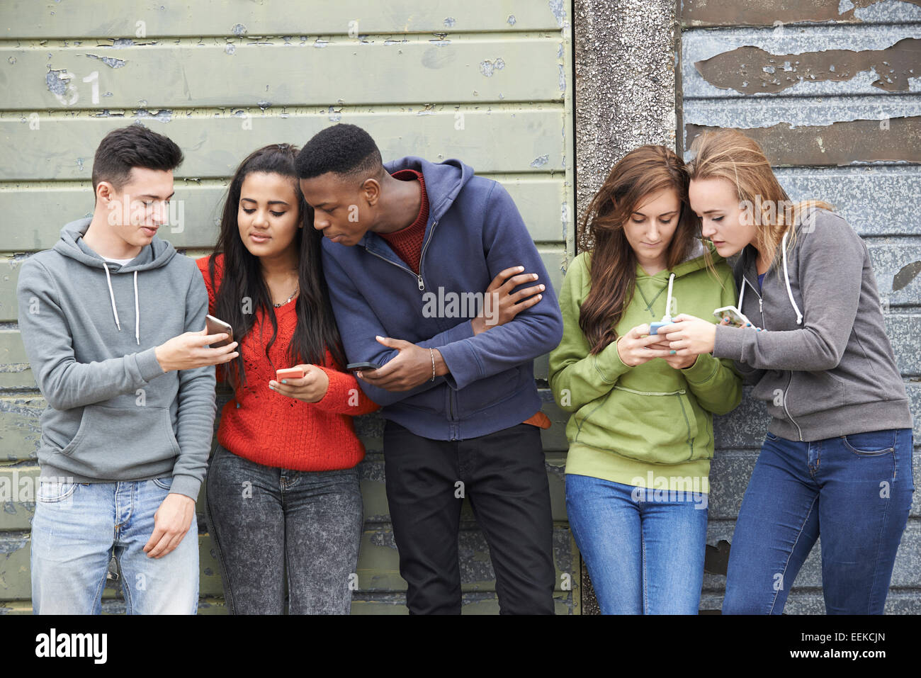 Group Of Teenagers Sharing Text Message On Mobile Phones Stock Photo ...