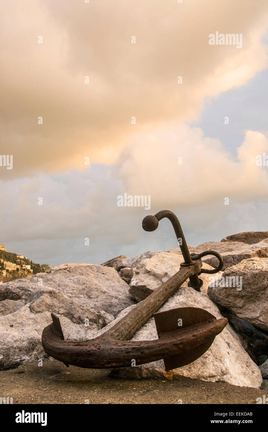 A large boat anchor rests on rocks in the harbor at Maori, Italy Stock ...
