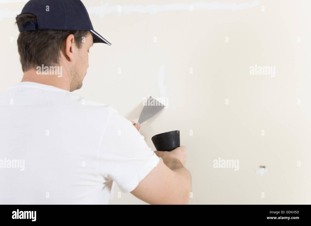 Man on a ladder spackles with a spatula cracks Stock Photo - Alamy