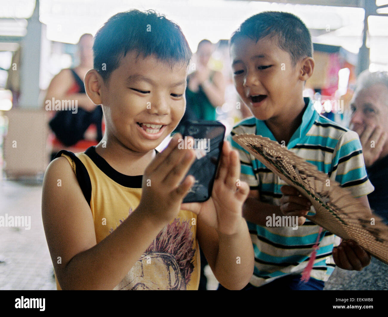 Two Vietnamese boys happily playing with smart phone while tourists ...