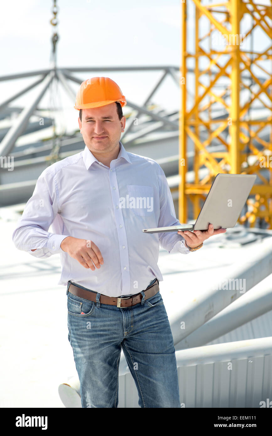A foreman with laptop at the construction supervising the project Stock ...