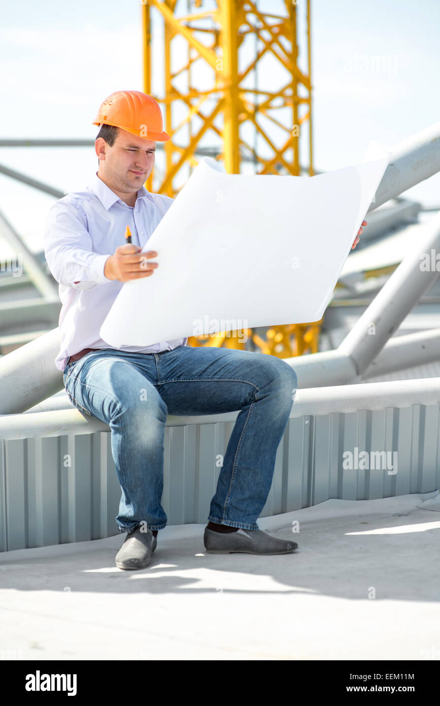 A foreman with drawings supervising the project at the construction ...