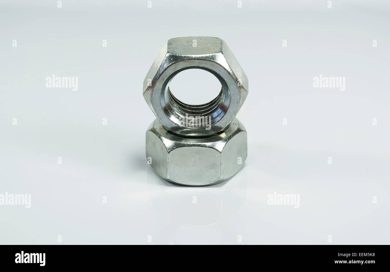 Two big, metallic nuts one placed on top of the other, isolated on ...