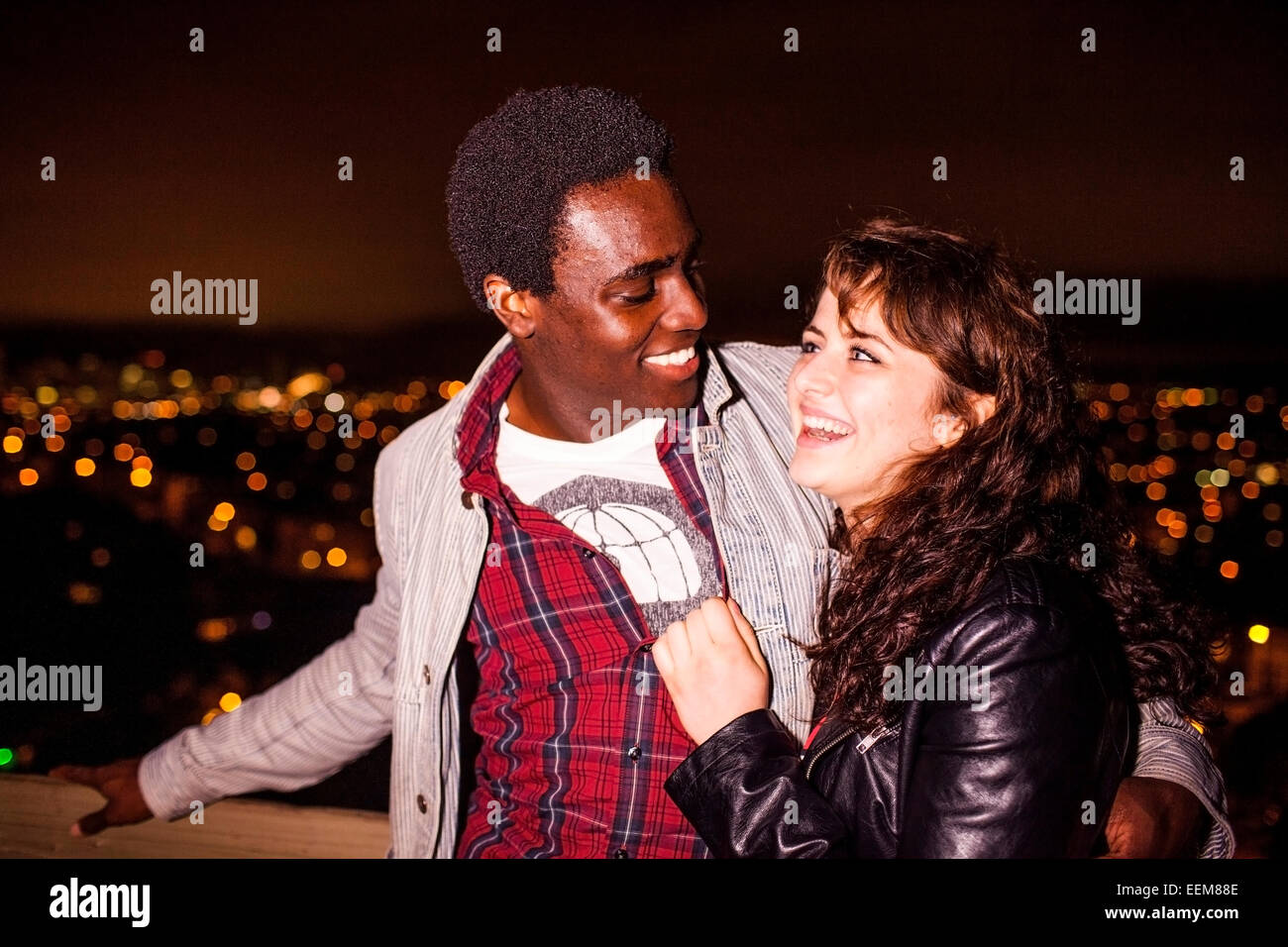 Couple hugging near scenic view of cityscape at night Stock Photo - Alamy