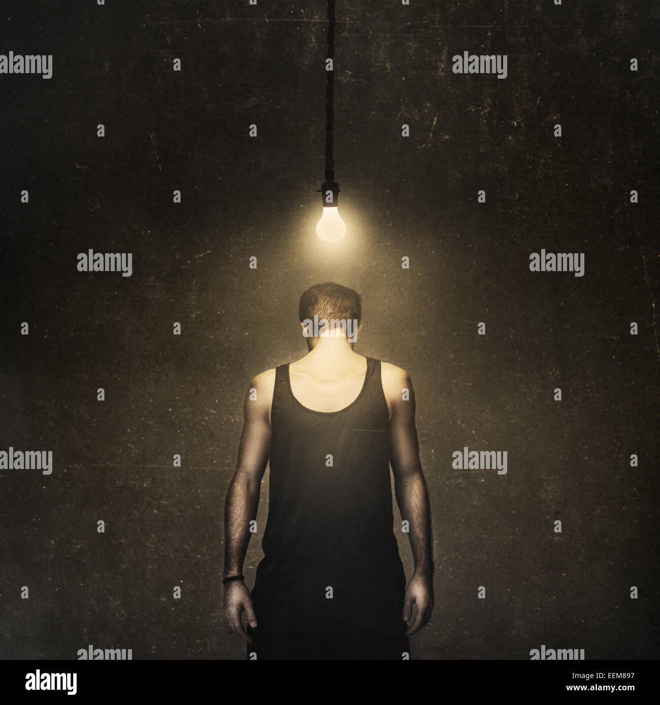 Front view of man standing under lightbulb with head turned around ...