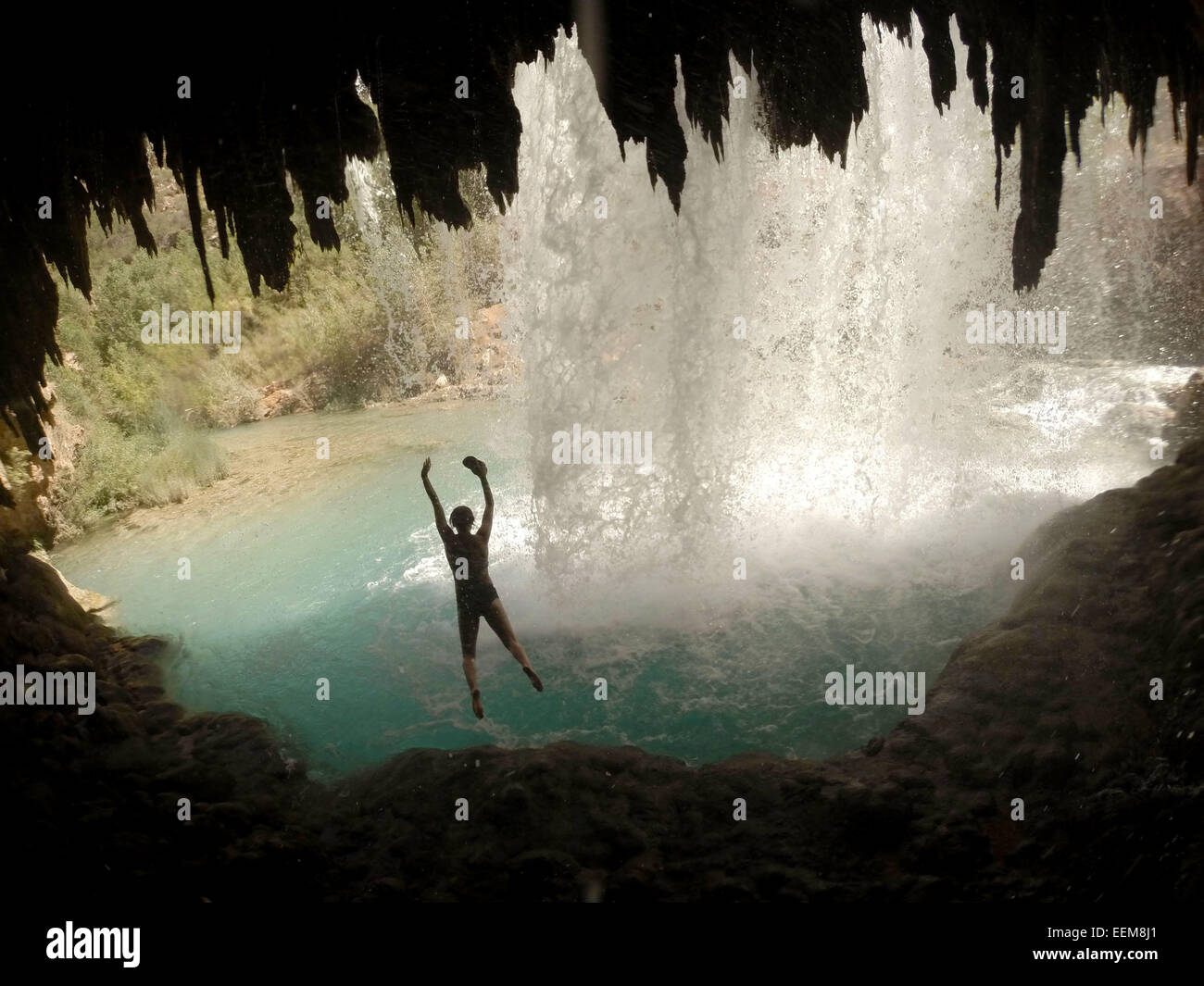Woman jumping into waterfall Stock Photo - Alamy