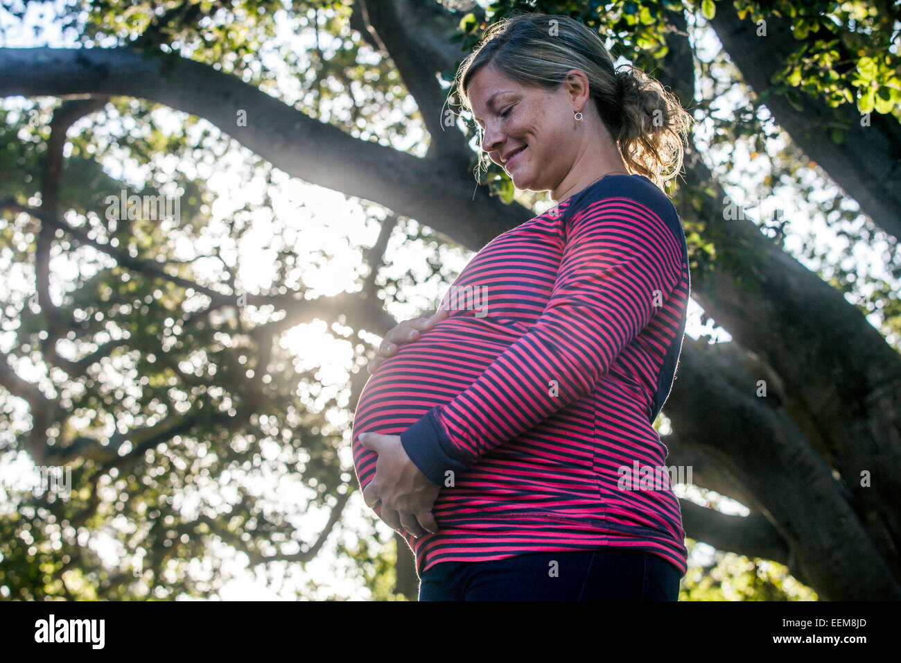 Low angle view of pregnant Caucasian mother holding her stomach ...