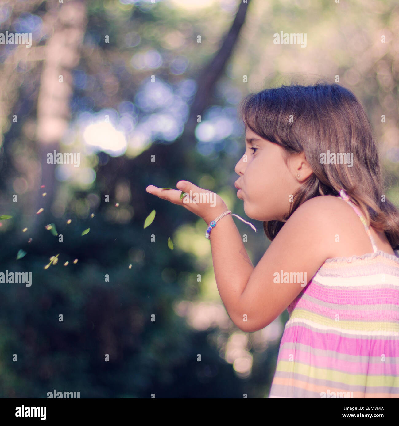 Girl standing outdoors blowing a handful of leaves Stock Photo - Alamy