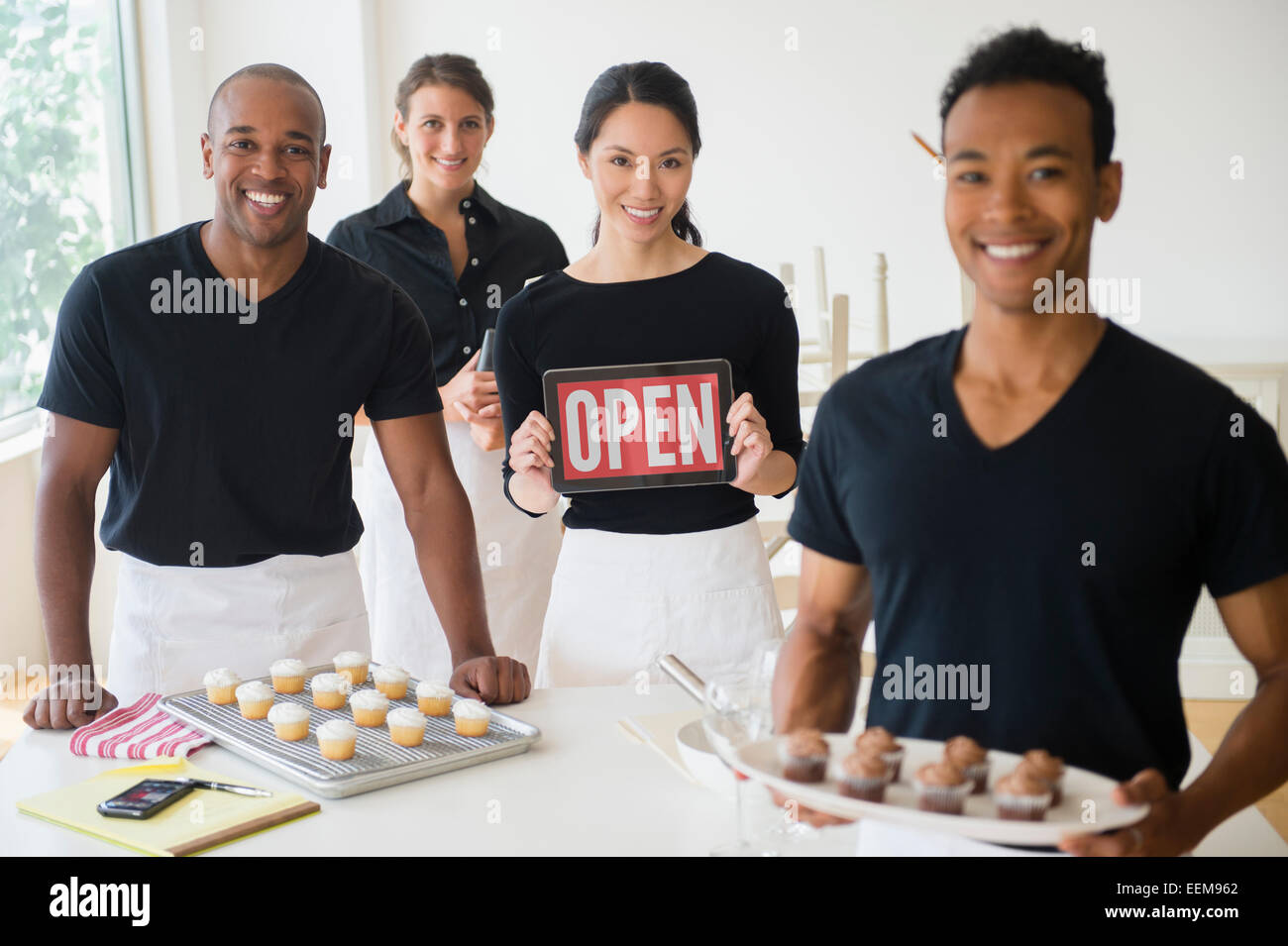 Caterers smiling together with food and open sign in event space Stock ...