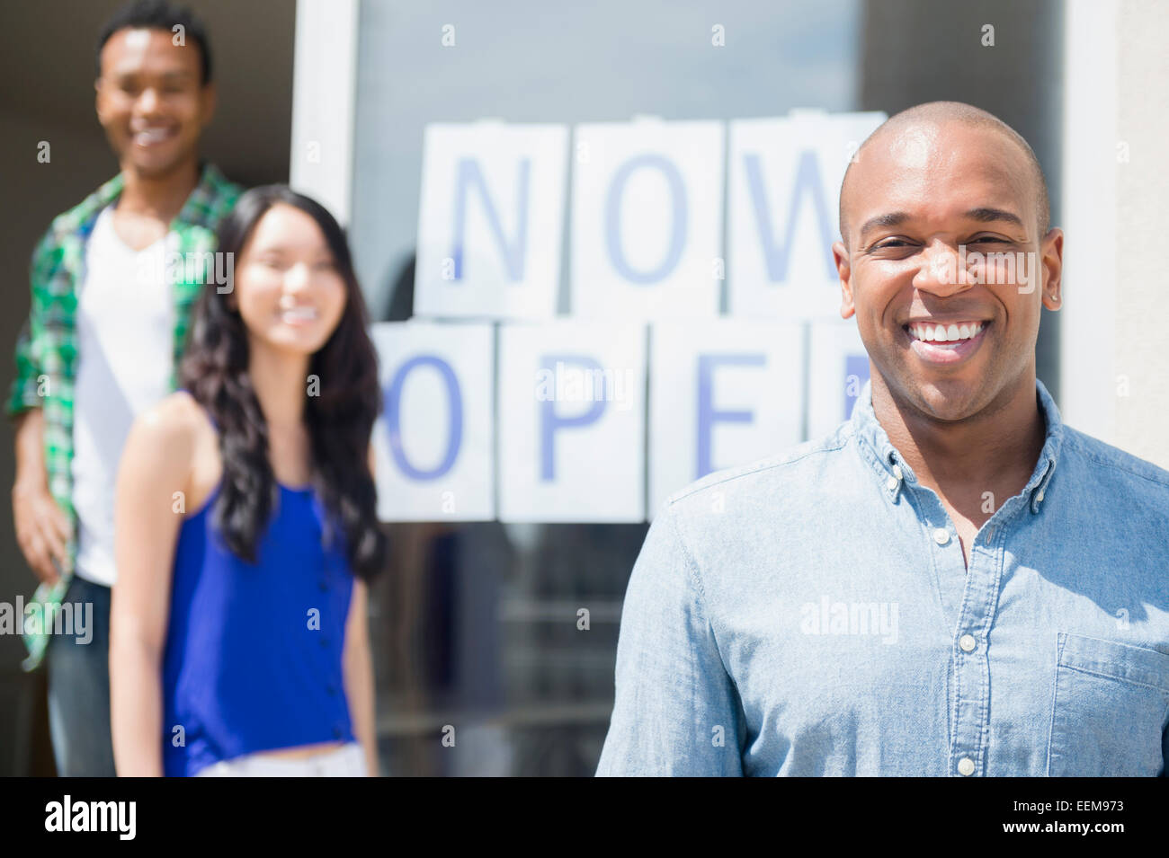 Friends smiling together by newly open storefront Stock Photo - Alamy