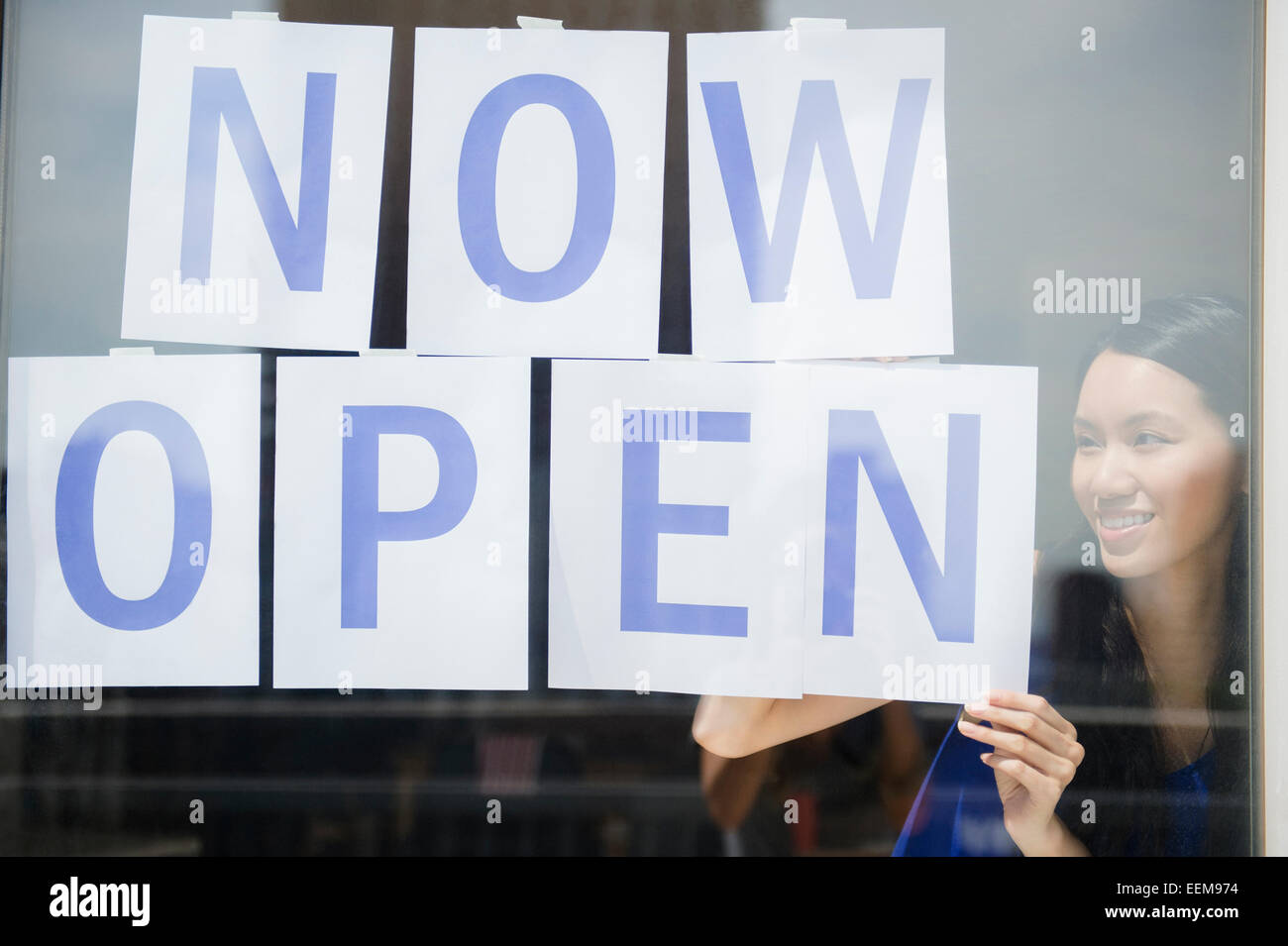 Woman hanging now open sign in store window Stock Photo - Alamy