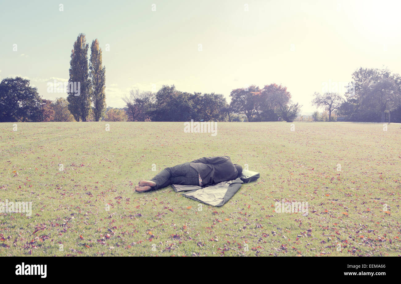 Man napping on coat in park field Stock Photo - Alamy