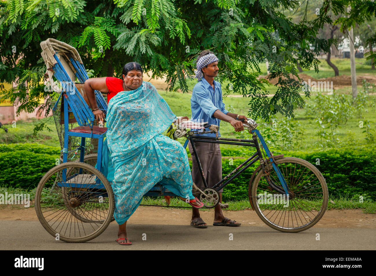 Sari-clad woman stepping down from a cycle rickshaw on the main avenue ...