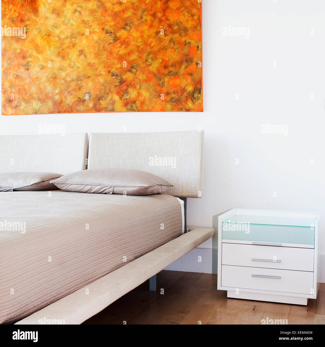 Bed, wall art and side table in modern bedroom Stock Photo - Alamy