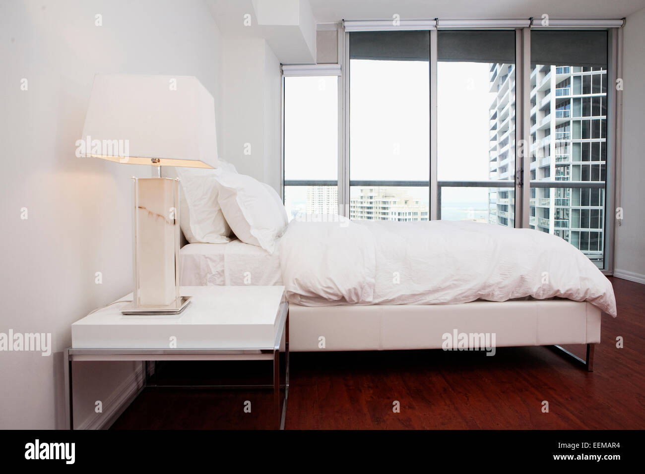 Windows, night table and bed in modern bedroom Stock Photo - Alamy