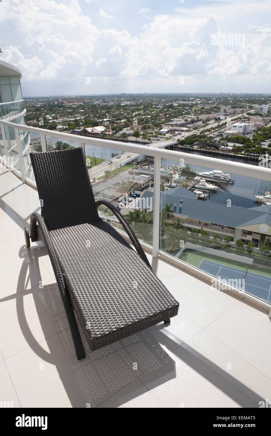 Deck chair on balcony overlooking cityscape Stock Photo - Alamy