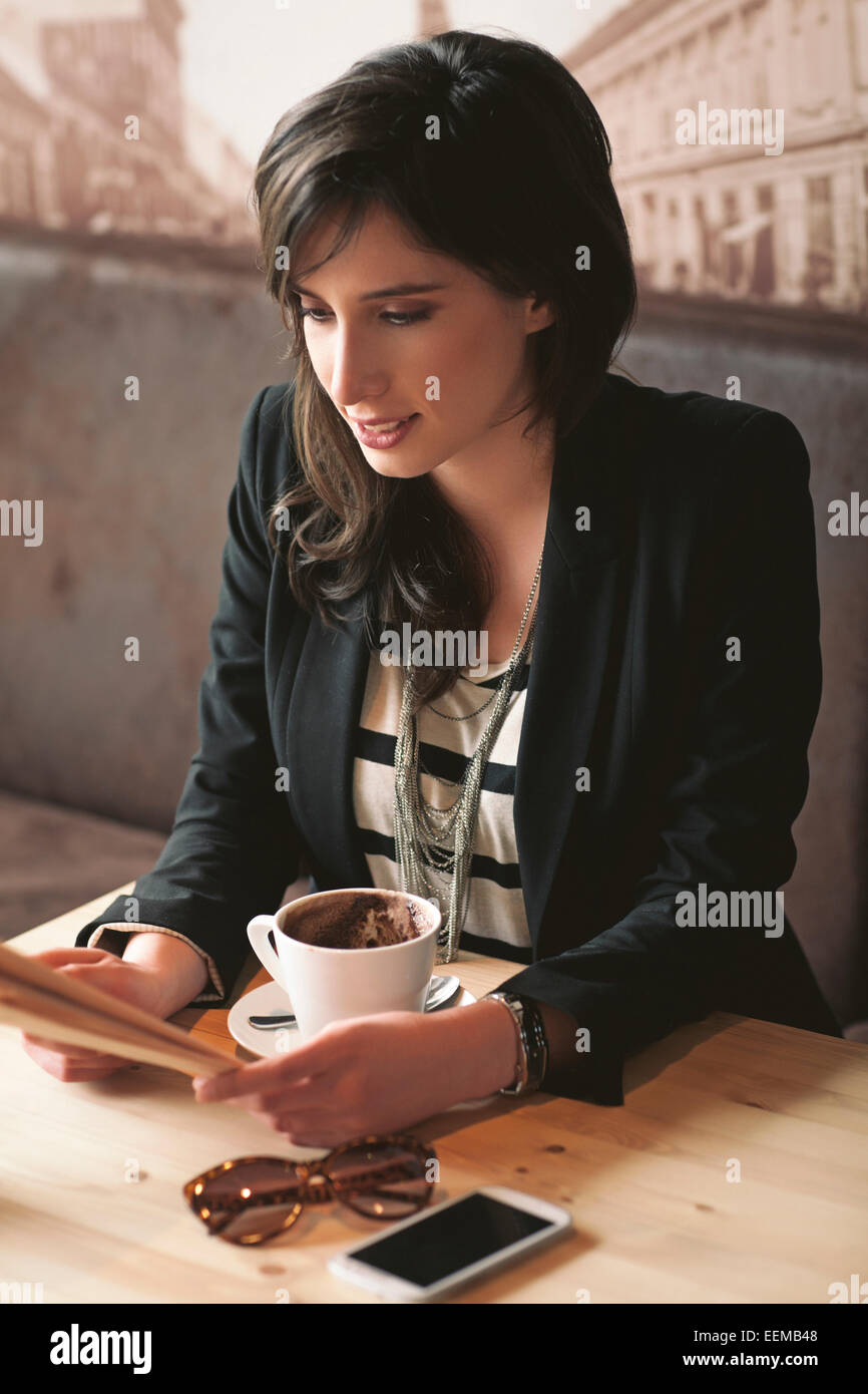 Woman reading with cup of coffee in cafe Stock Photo - Alamy