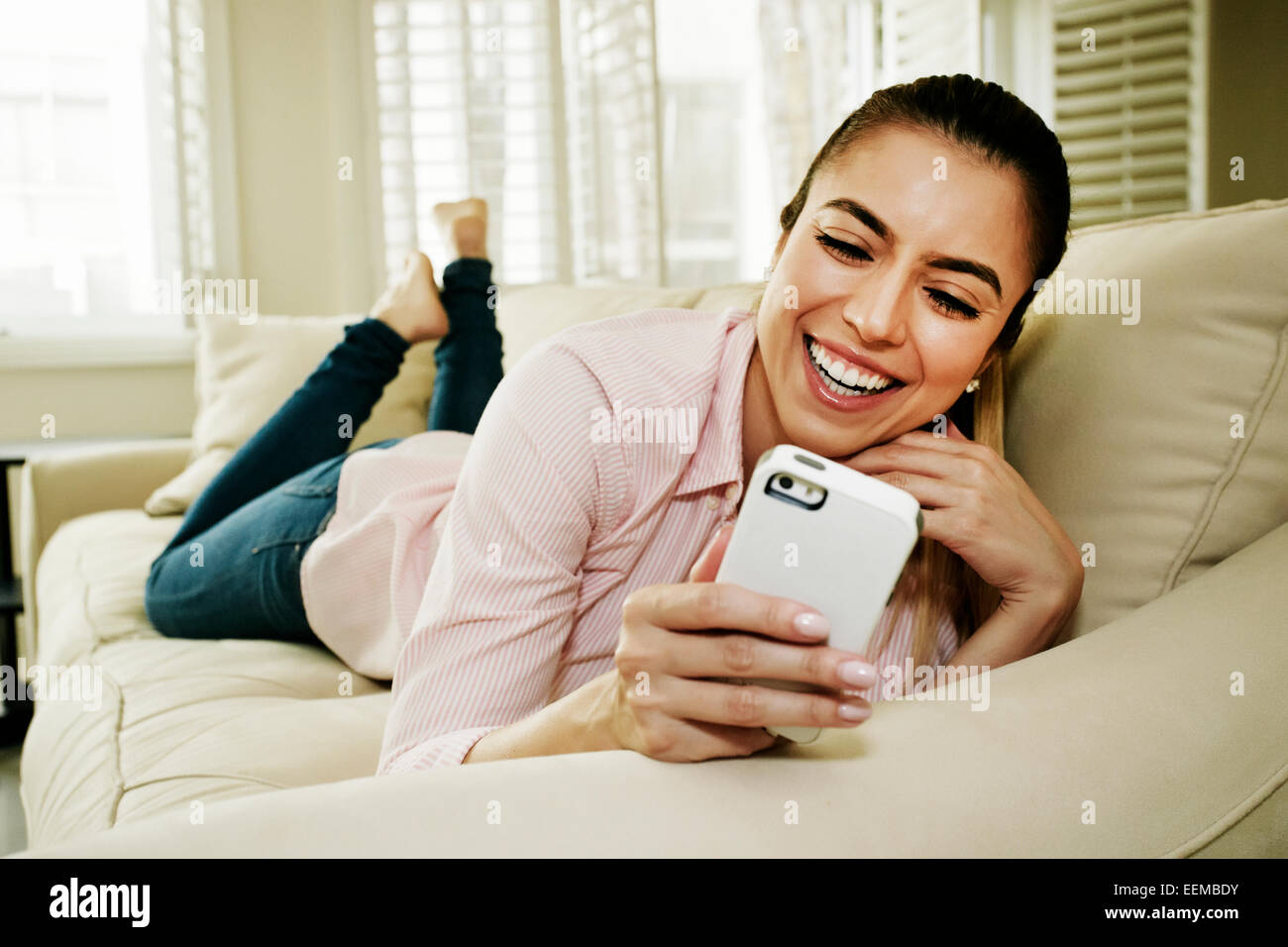 Caucasian woman using cell phone on sofa Stock Photo - Alamy