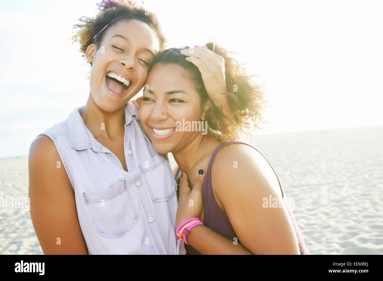 Smiling friends hugging at beach Stock Photo - Alamy