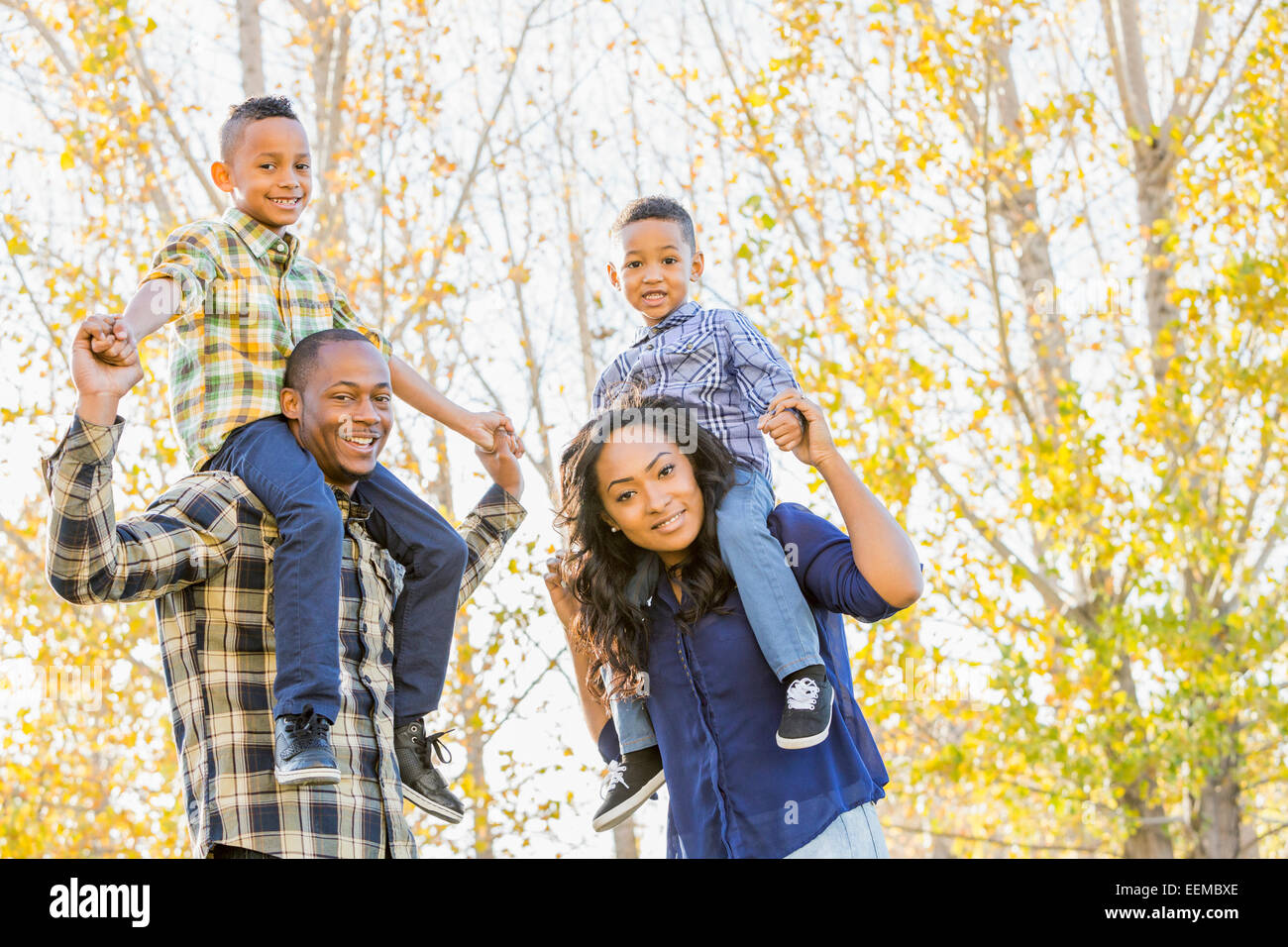 Parents carrying children on shoulders near autumn trees Stock Photo ...