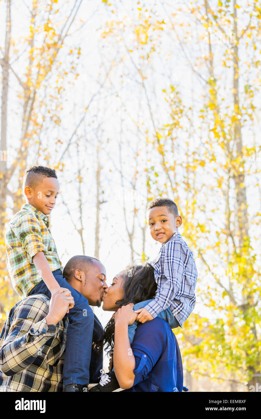 Parents carrying children on shoulders near autumn trees Stock Photo ...