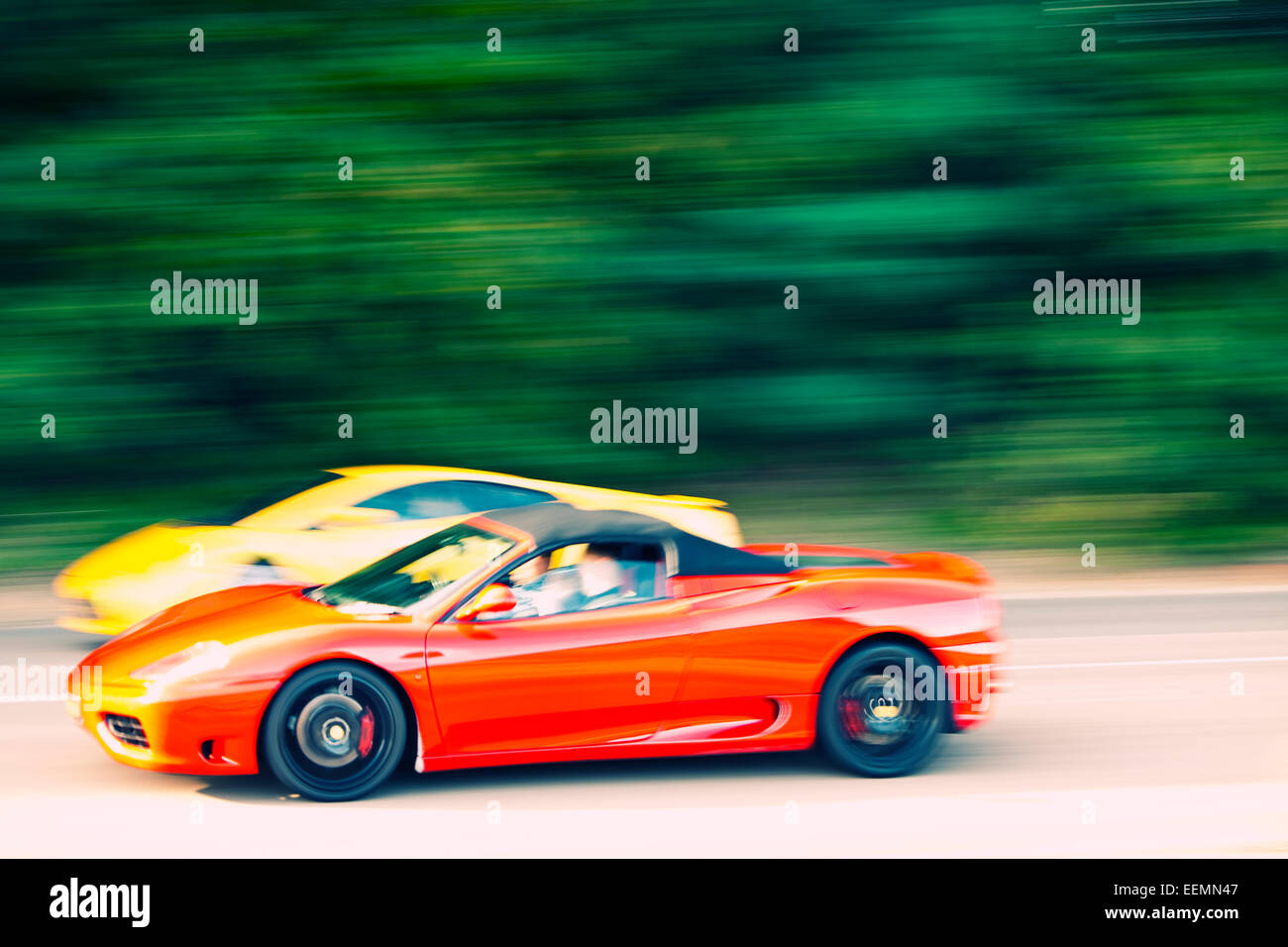 Red and yellow car driving fast on country road Stock Photo - Alamy