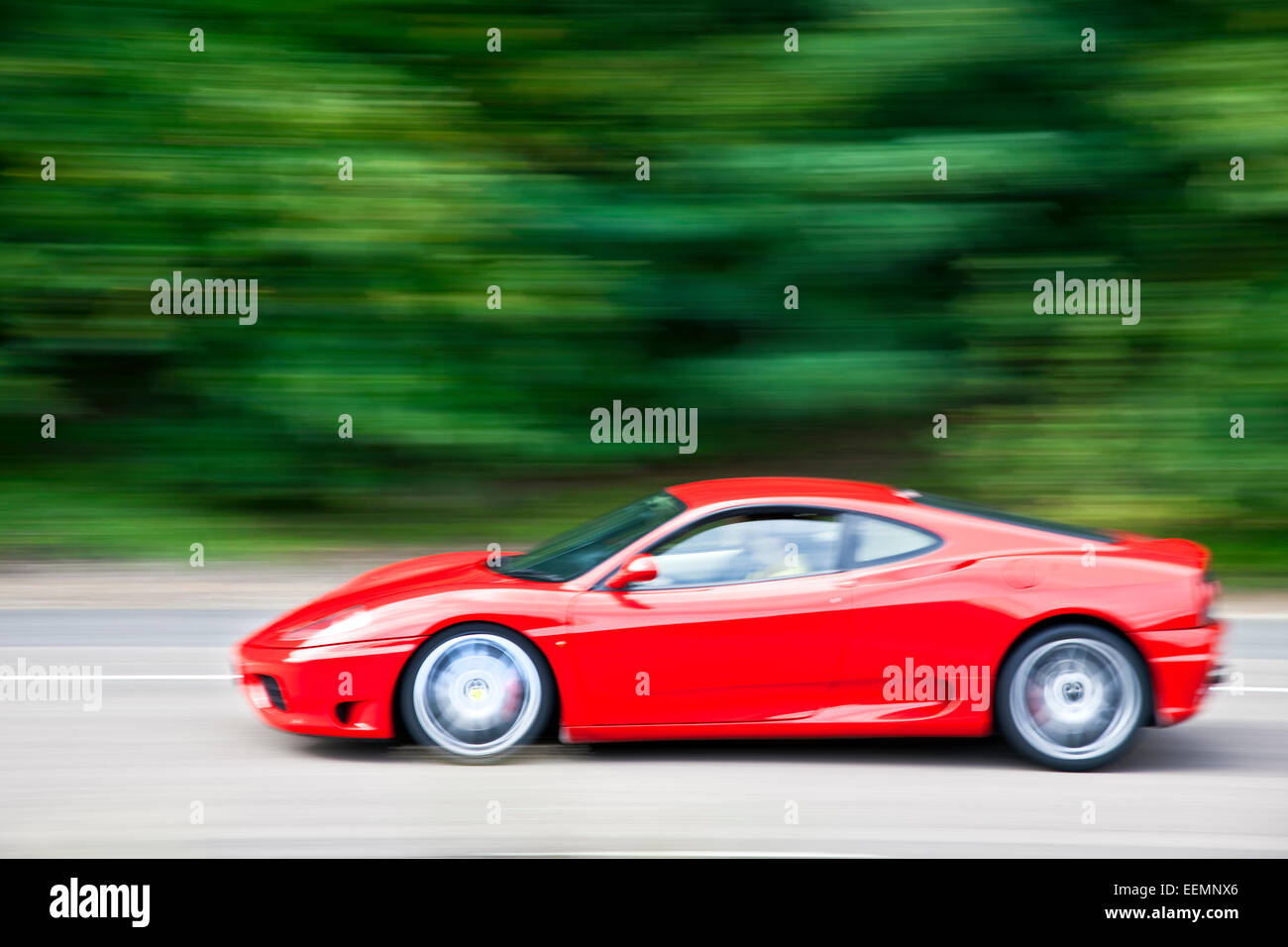 Red car driving fast on country road Stock Photo - Alamy
