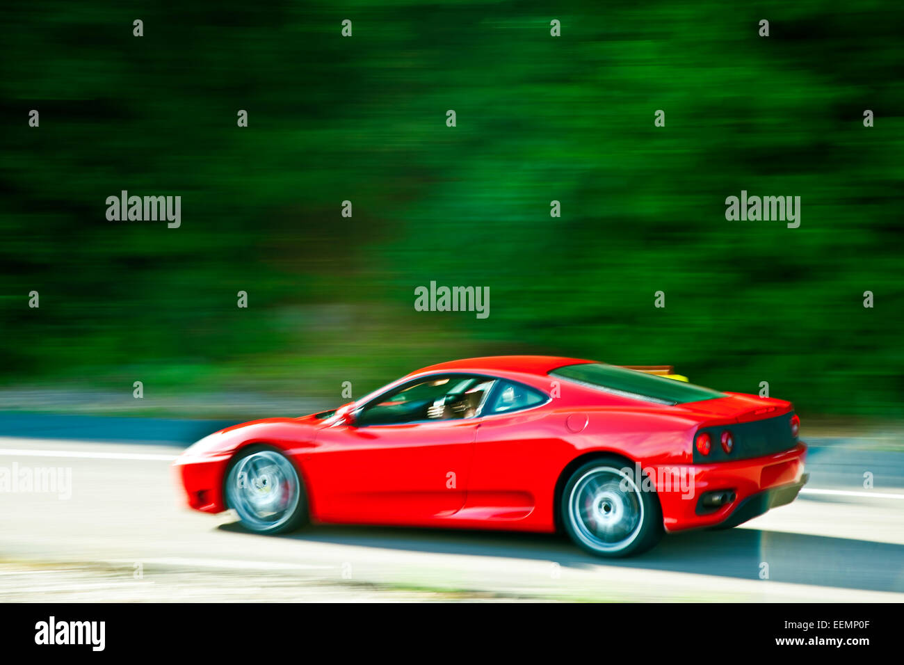 Red car driving fast on country road Stock Photo - Alamy