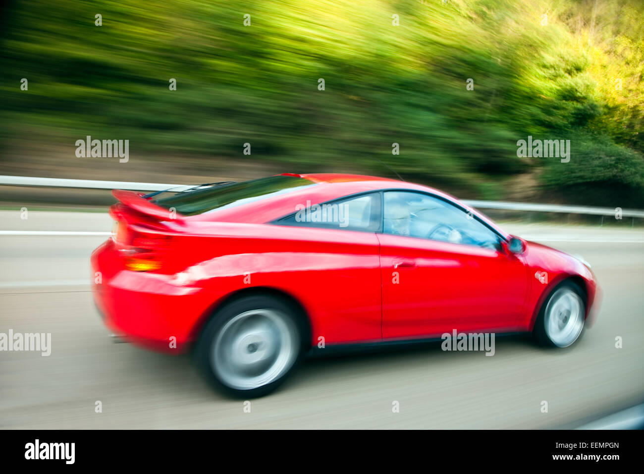 Red car driving fast on country road Stock Photo - Alamy