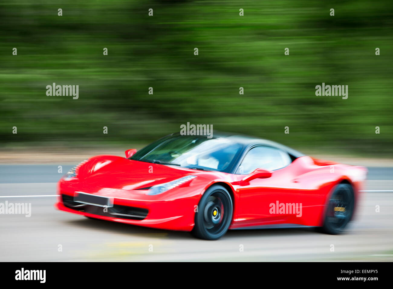 Red car driving fast on country road Stock Photo - Alamy