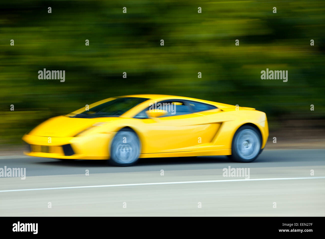 Yellow car driving fast on country road Stock Photo - Alamy