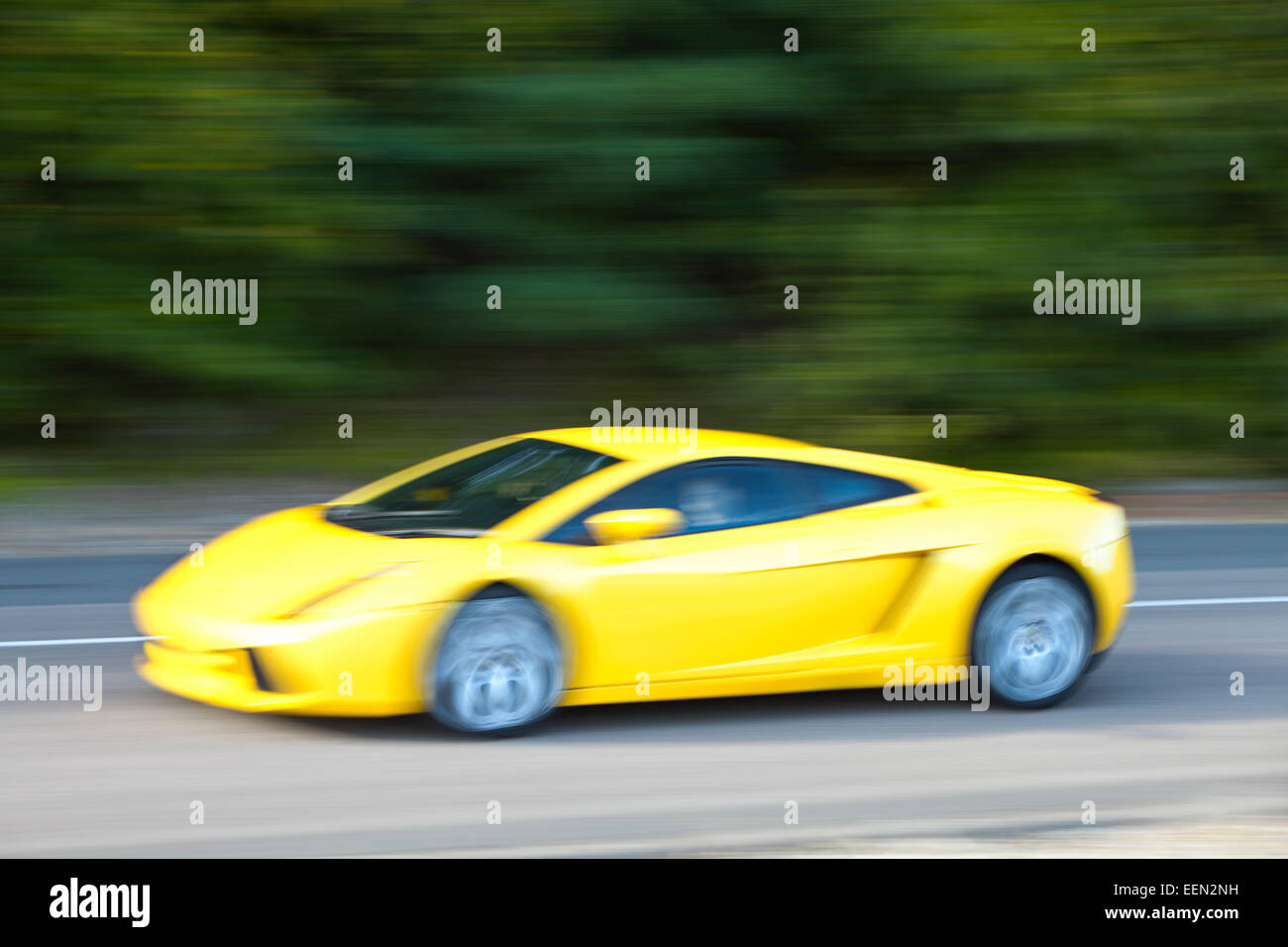 Yellow car driving fast on country road Stock Photo - Alamy