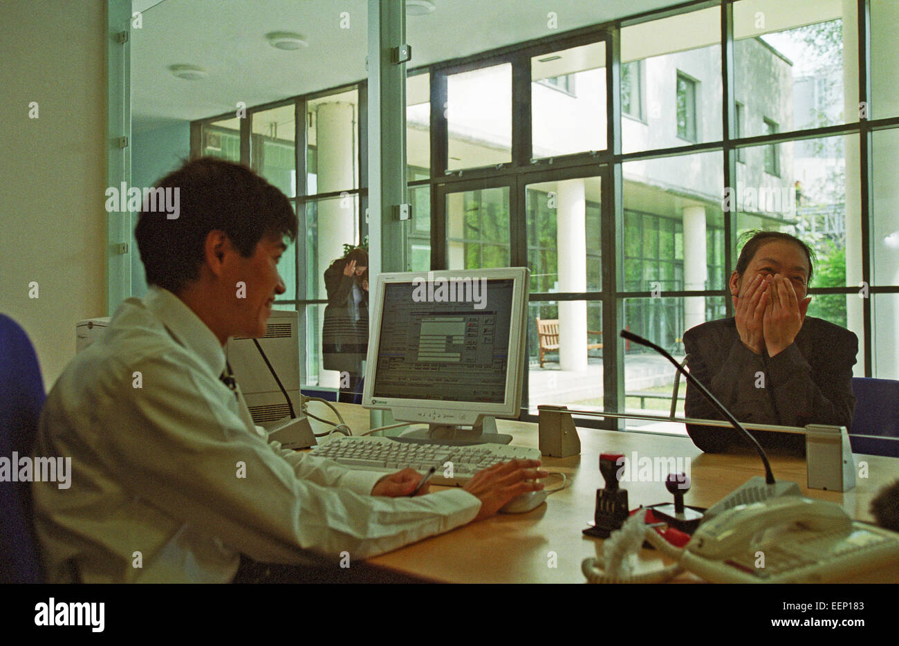 Local authority employee behind a counter shares a joke with an ...