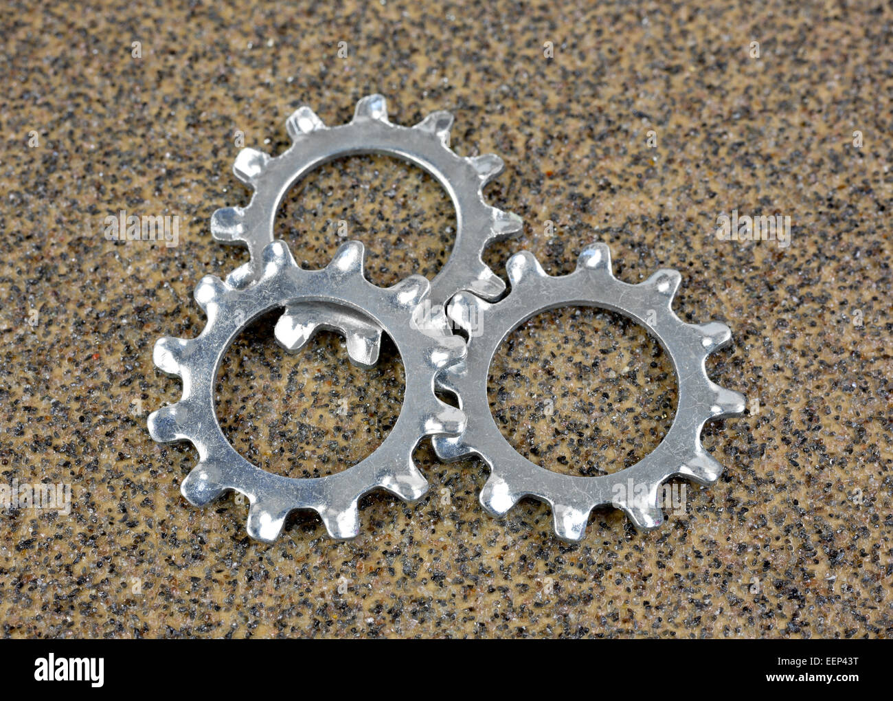 A group of three internal toothed lock washers on a piece of coarse ...