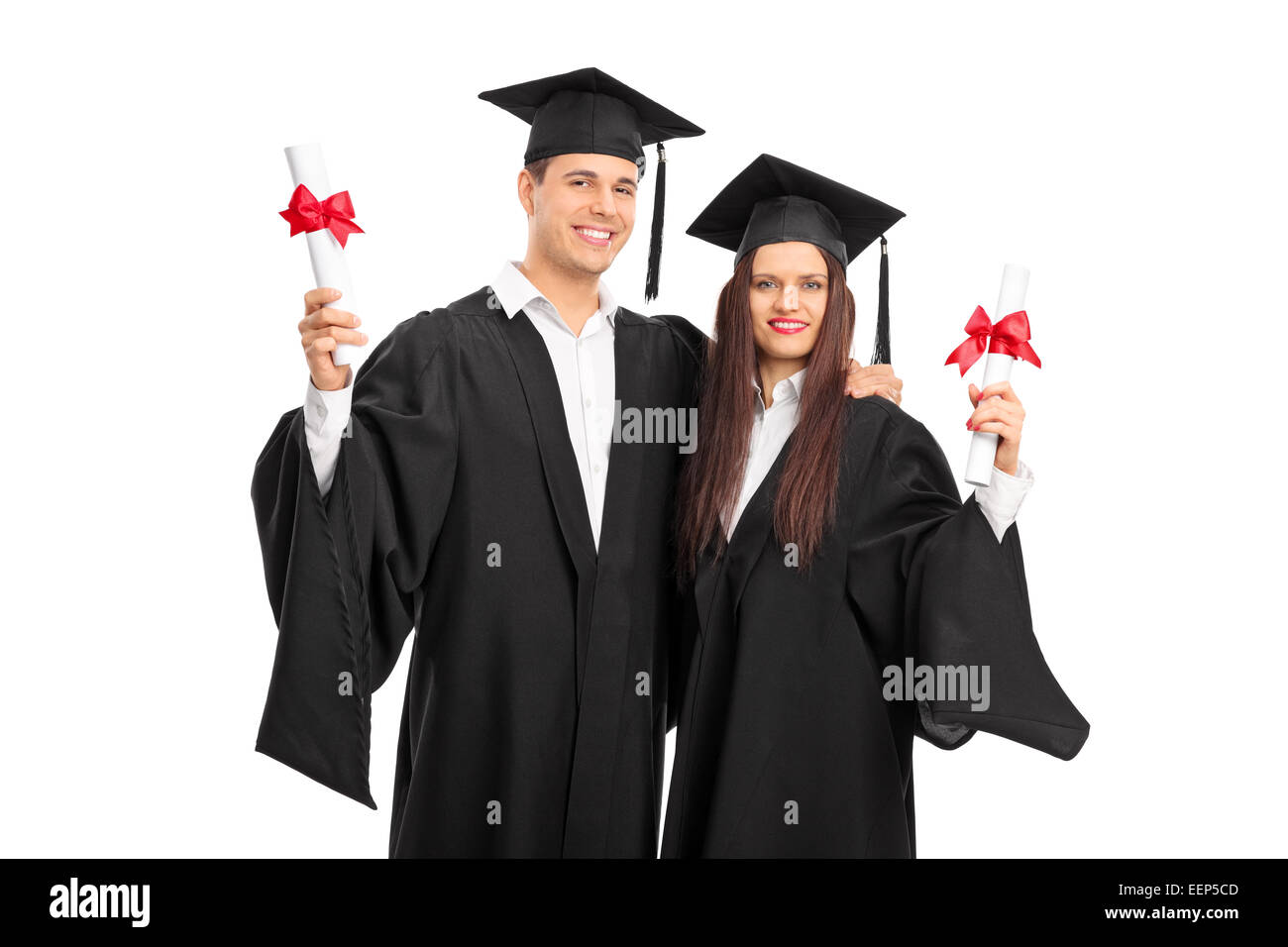 Couple in graduation gowns posing with diplomas isolated on white ...