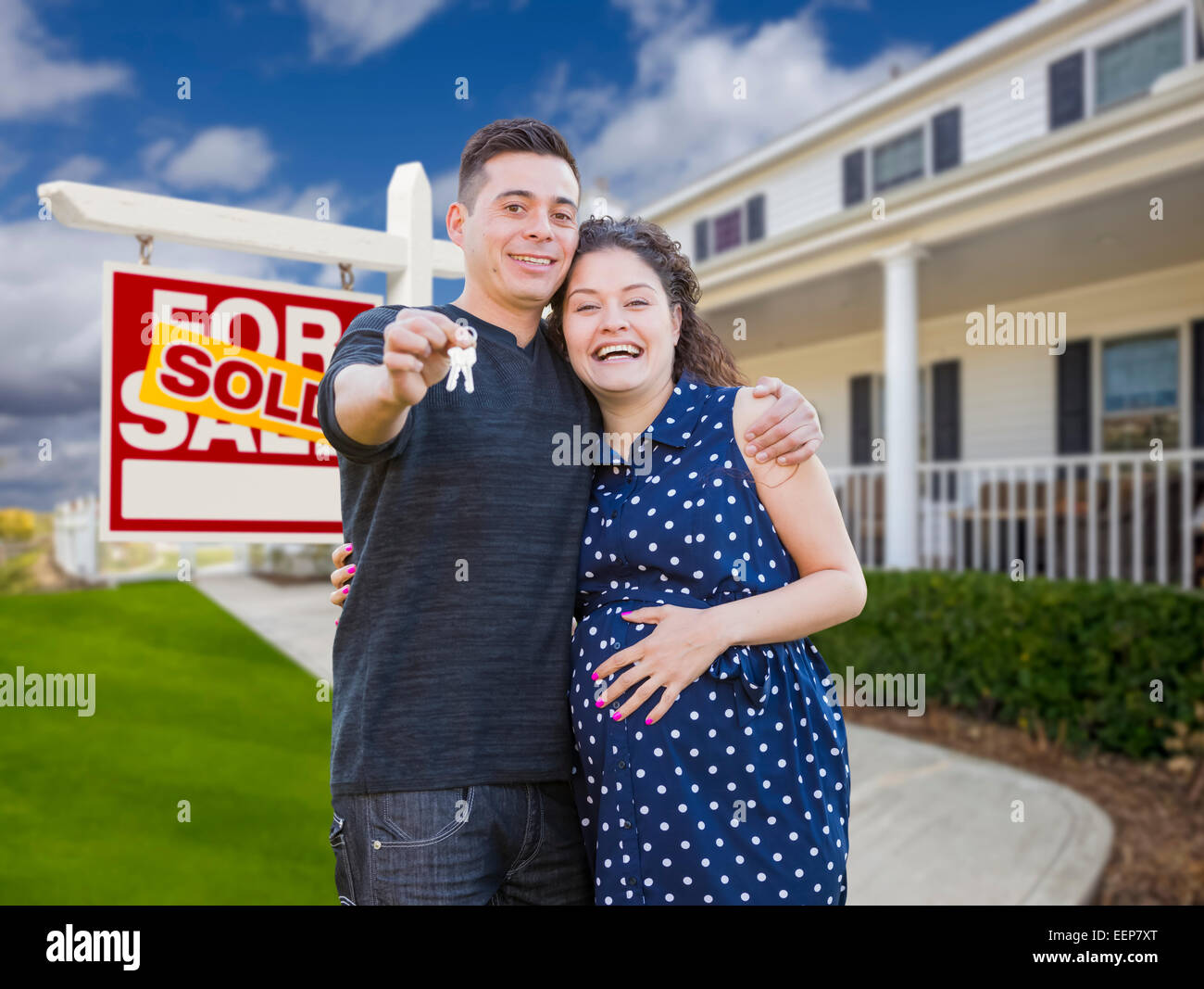 Happy Hispanic Couple In Front of New Home And Sold Real Estate Sign ...
