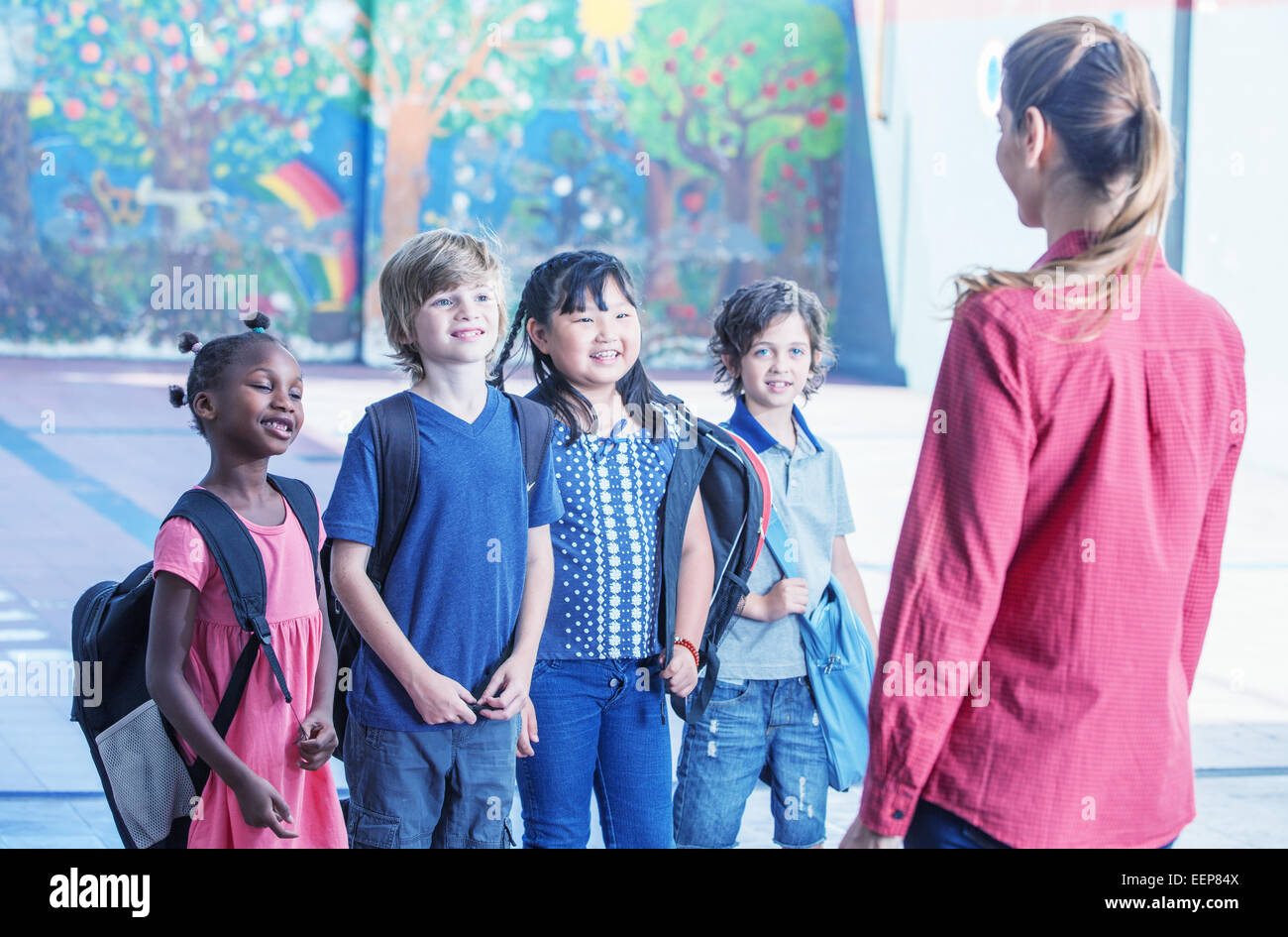 Female teacher explaining to multirace students in schoolyard Stock ...