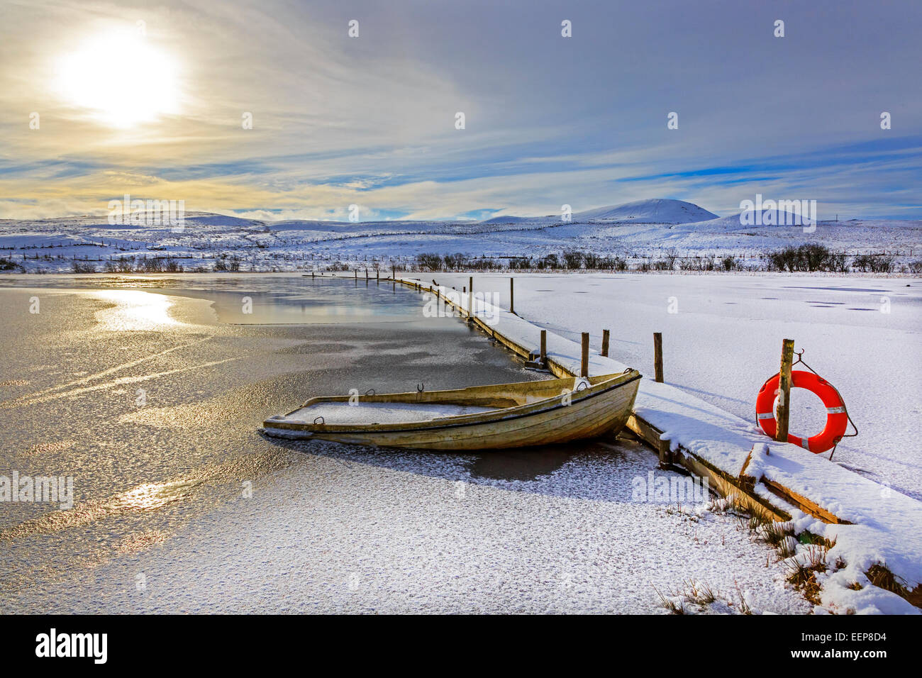 Small fishing rowing boat, sunk by the weight of snow, on a loch on ...