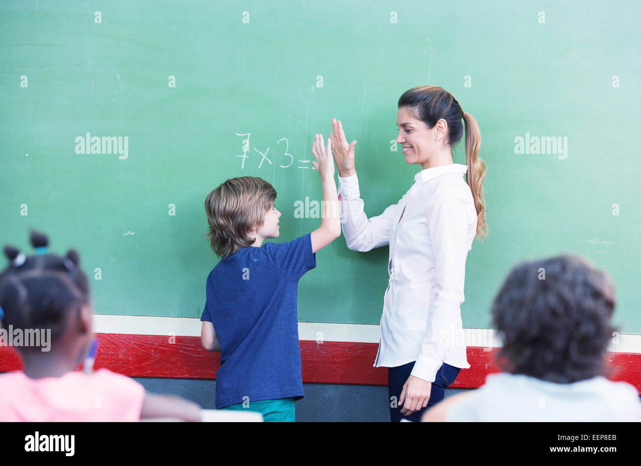 Teacher congratulating with kid in primary classroom Stock Photo - Alamy
