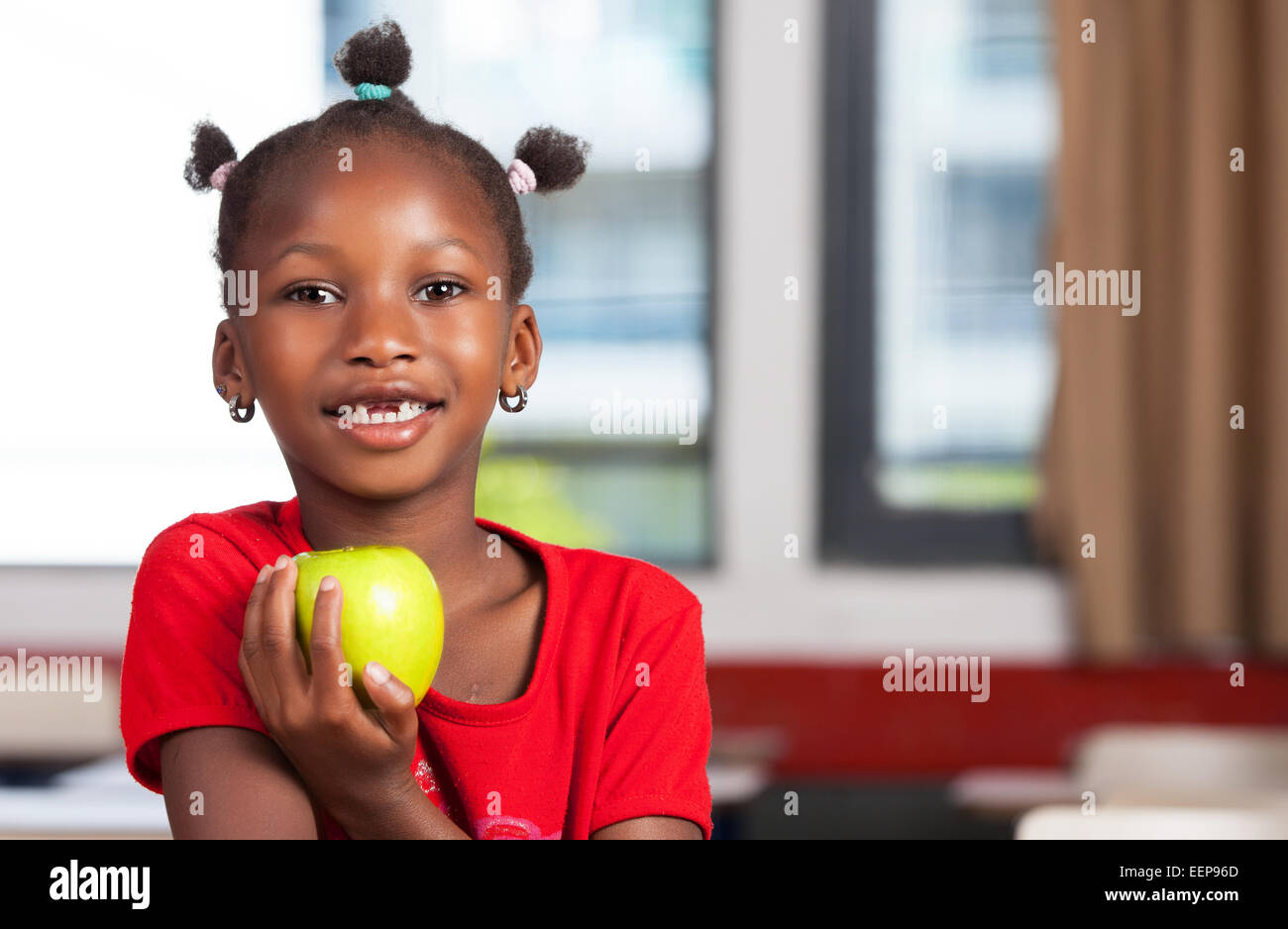 African girl at school desk ready to eat her apple Stock Photo - Alamy