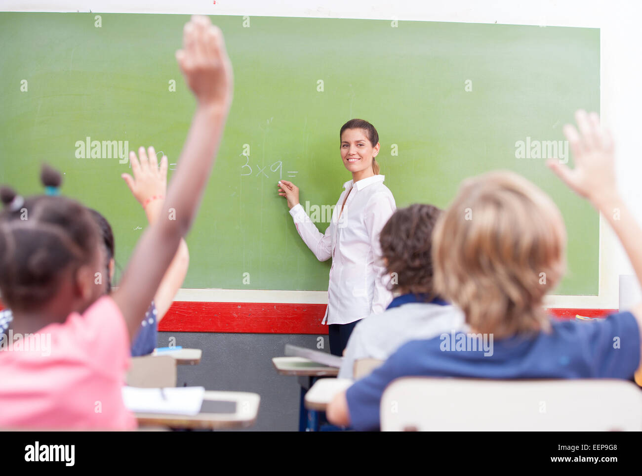 Intelligent group of young school children raising their hands in the ...