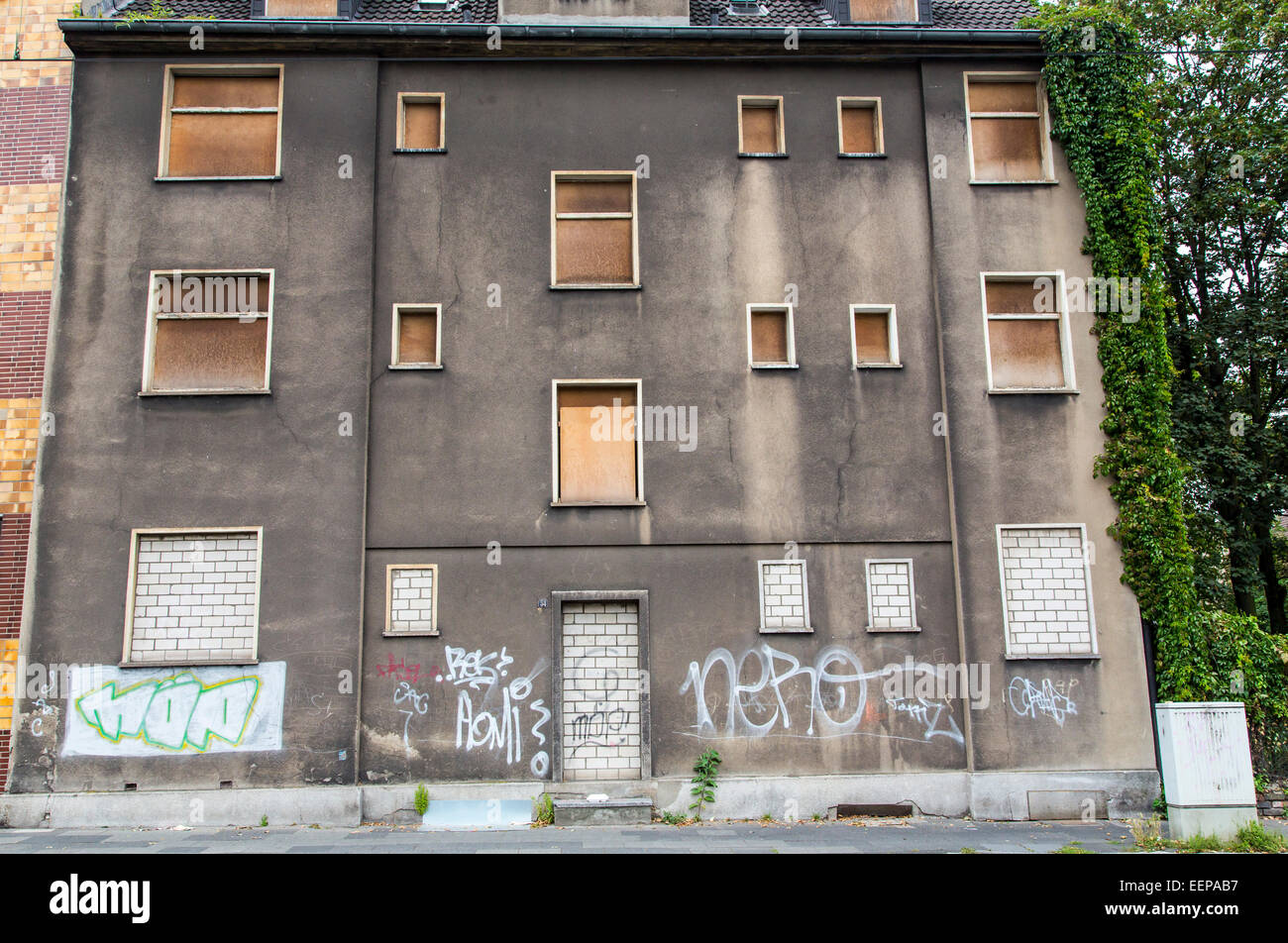 Empty house, run down, doors and windows are bricked and partly covered ...