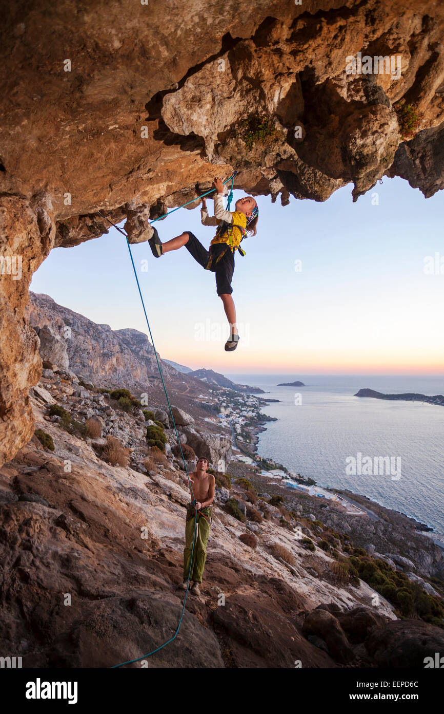 Seven-year old girl climbing a challenging route, father belaying ...