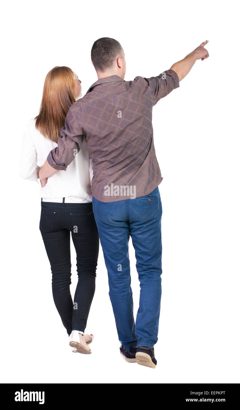 Back view of walking young couple (man and woman) pointing. Rear view ...