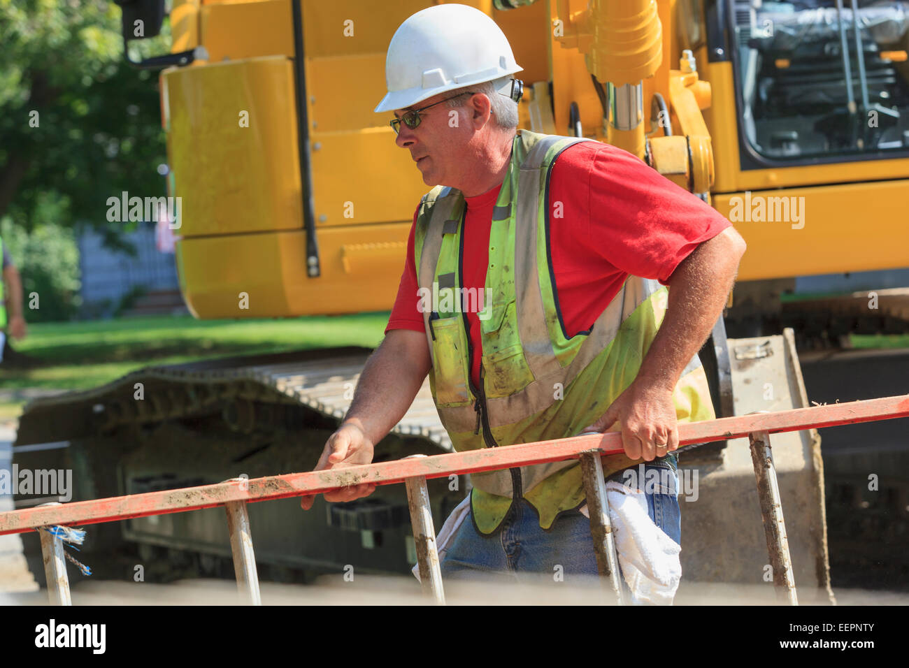 Construction worker on site carrying ladder Stock Photo - Alamy
