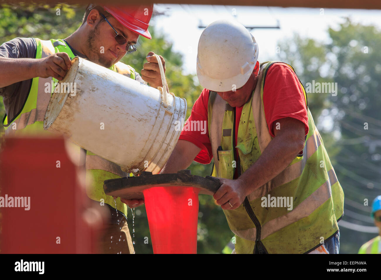 Construction workers pouring water to prime a pump Stock Photo - Alamy