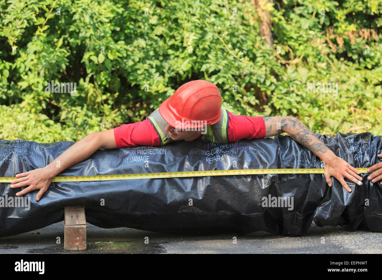 Construction worker measuring length of water main section Stock Photo ...