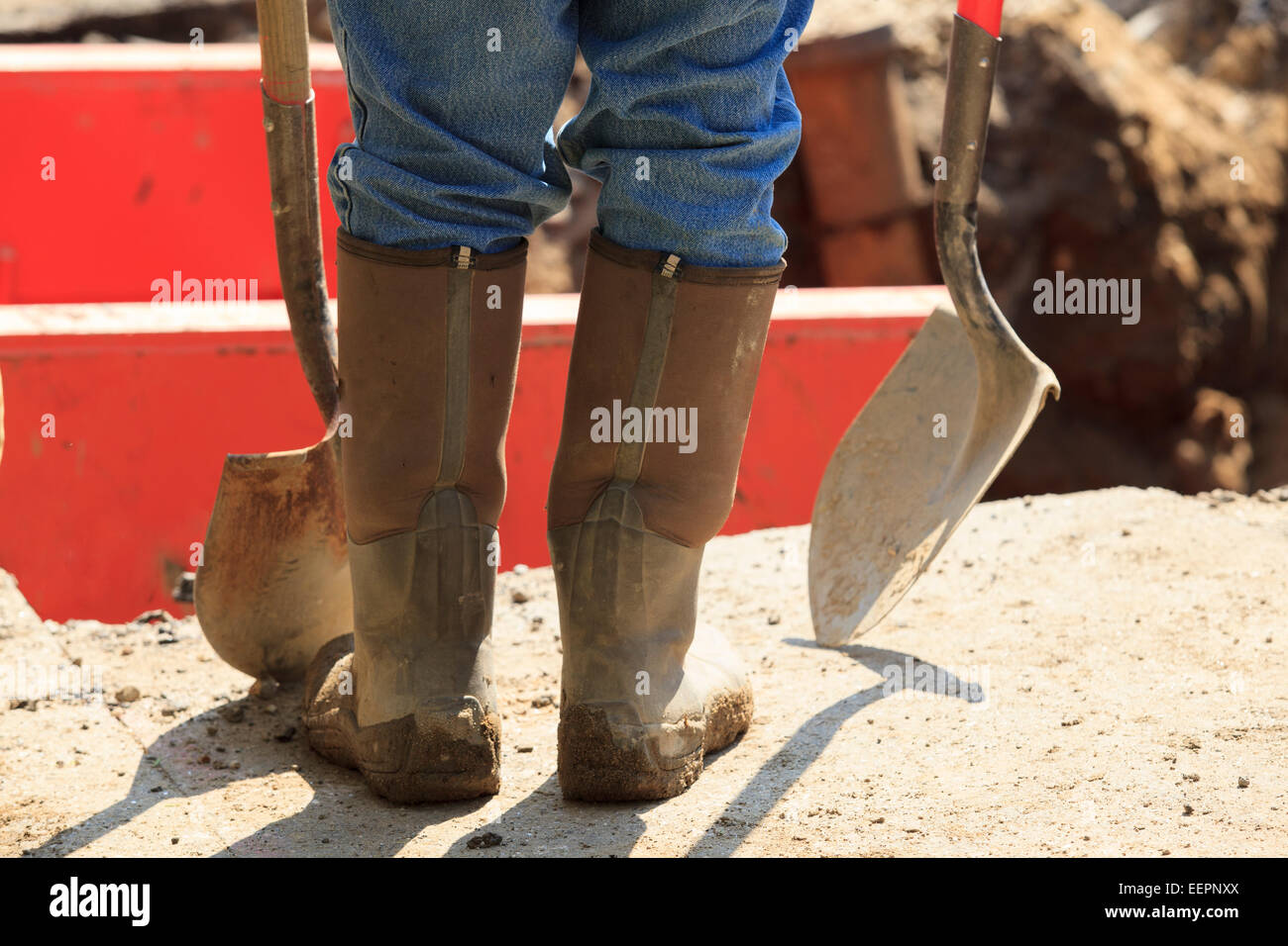 Construction worker preparing to enter shored up hole with shovels ...