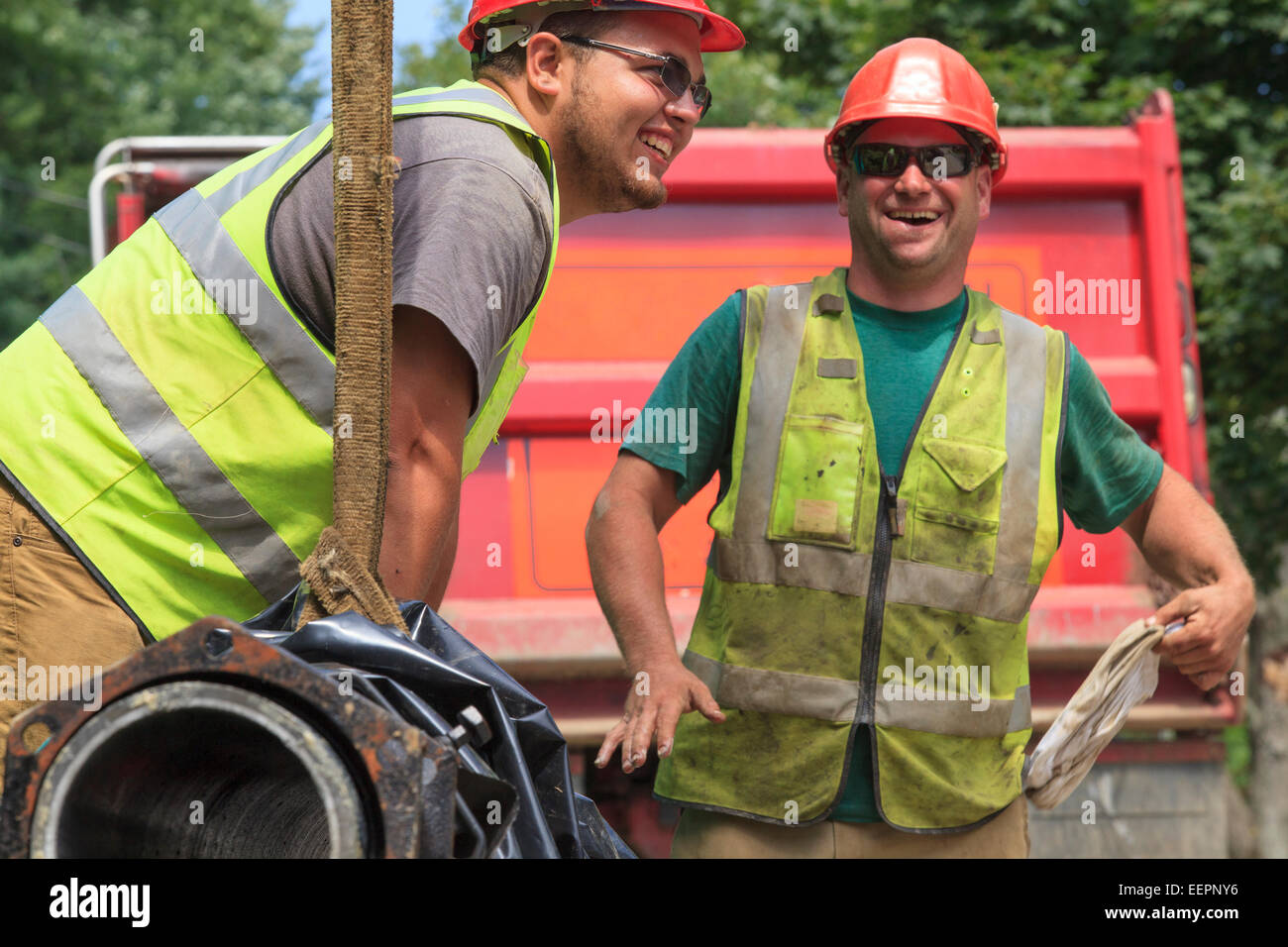 Construction workers guiding water main into place Stock Photo - Alamy