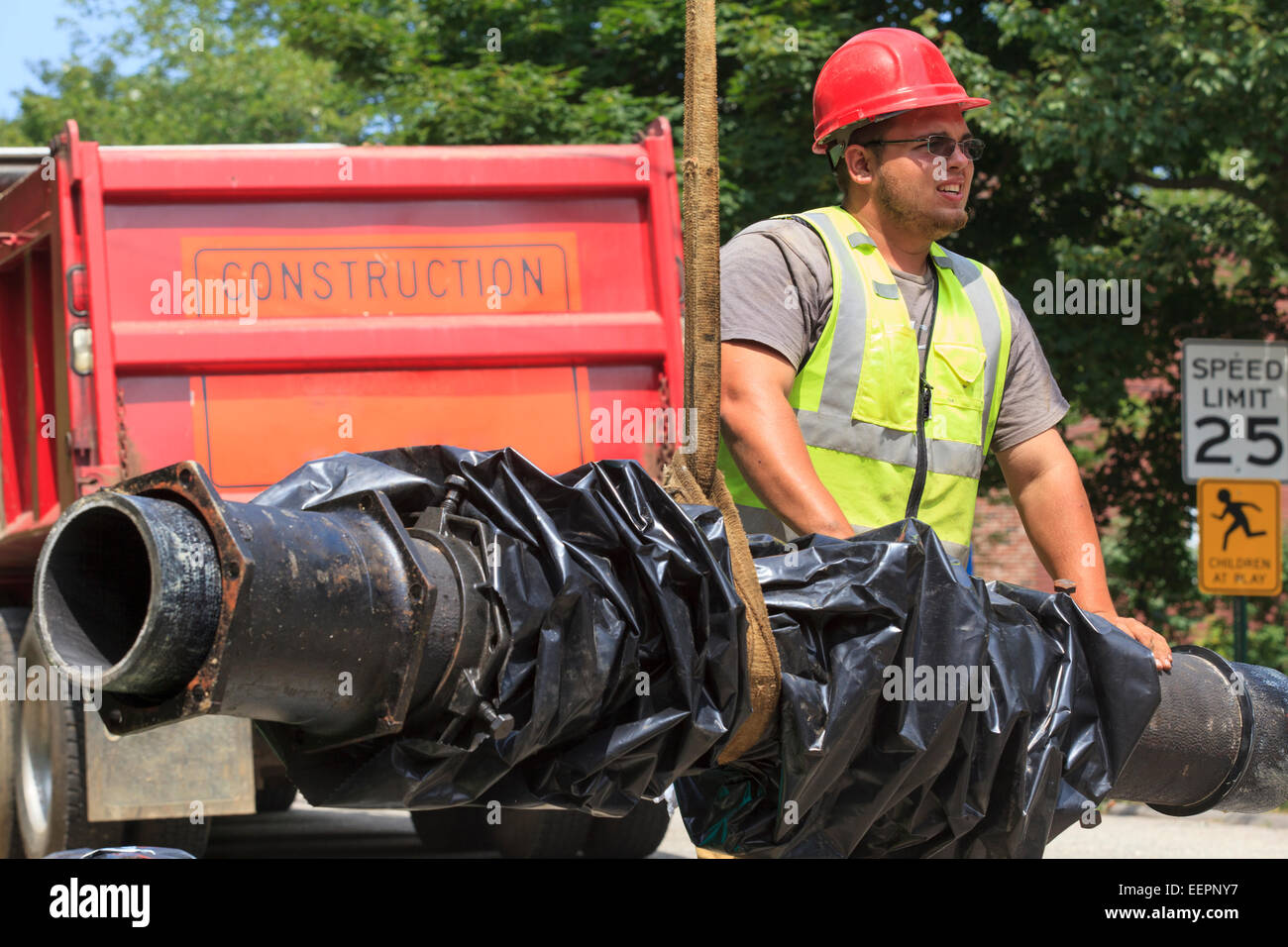 Construction worker guiding water main into place Stock Photo - Alamy